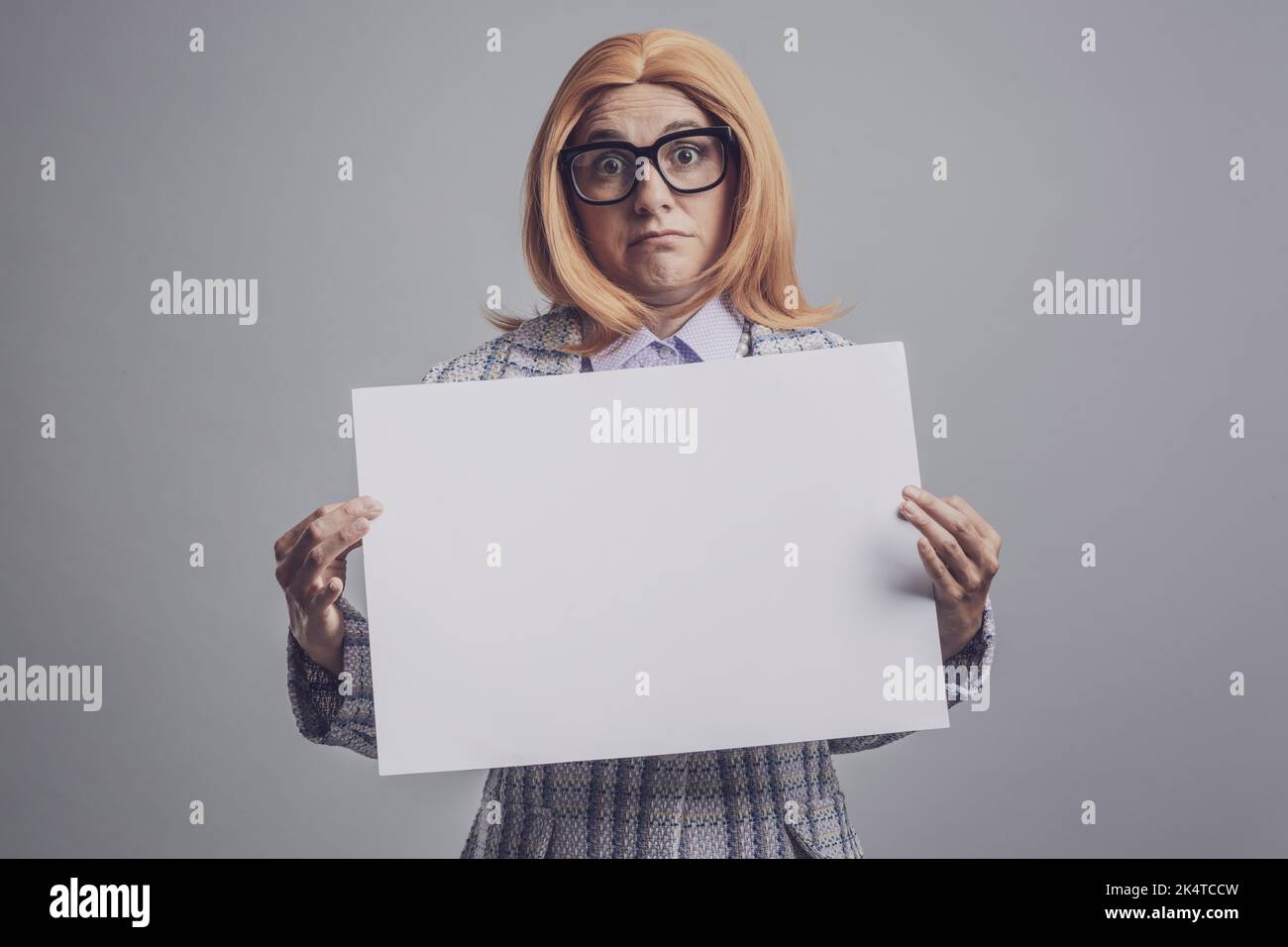 Funny disappointed woman holding a blank sign and looking at camera ...