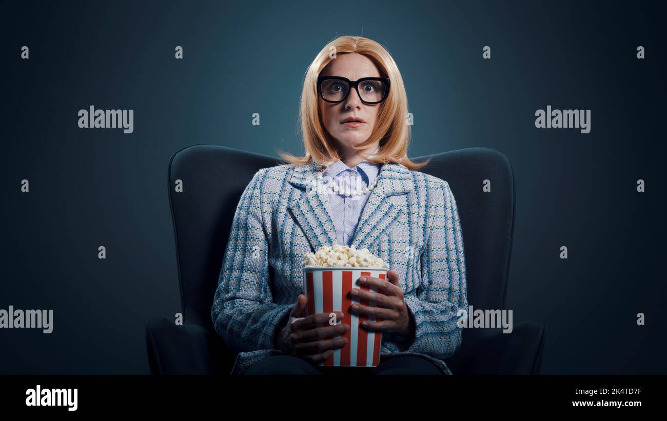 Funny woman watching a suspense movie and eating popcorn at the movie ...