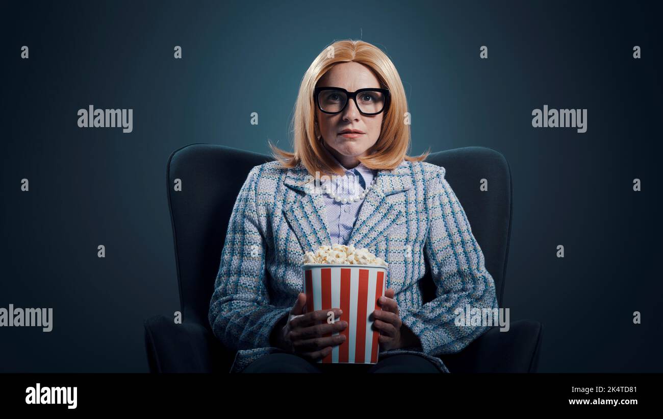 Funny woman watching a suspense movie and eating popcorn at the movie ...