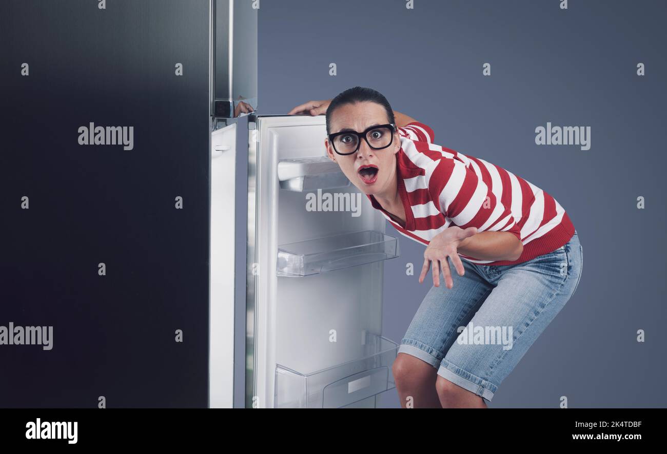 Shocked disappointed woman looking in the empty fridge at home Stock ...