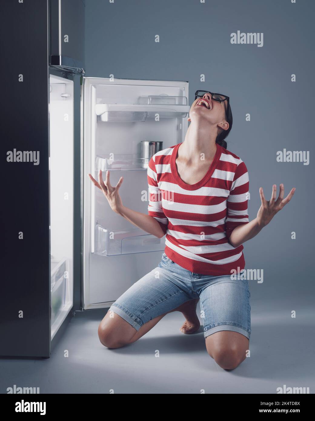 Desperate crying woman and empty fridge, she is hungry but she has no ...