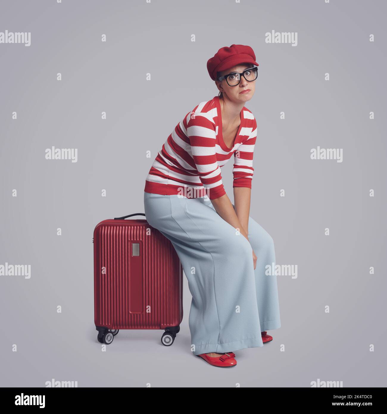 Sad disappointed traveler woman sitting on her suitcase and waiting ...