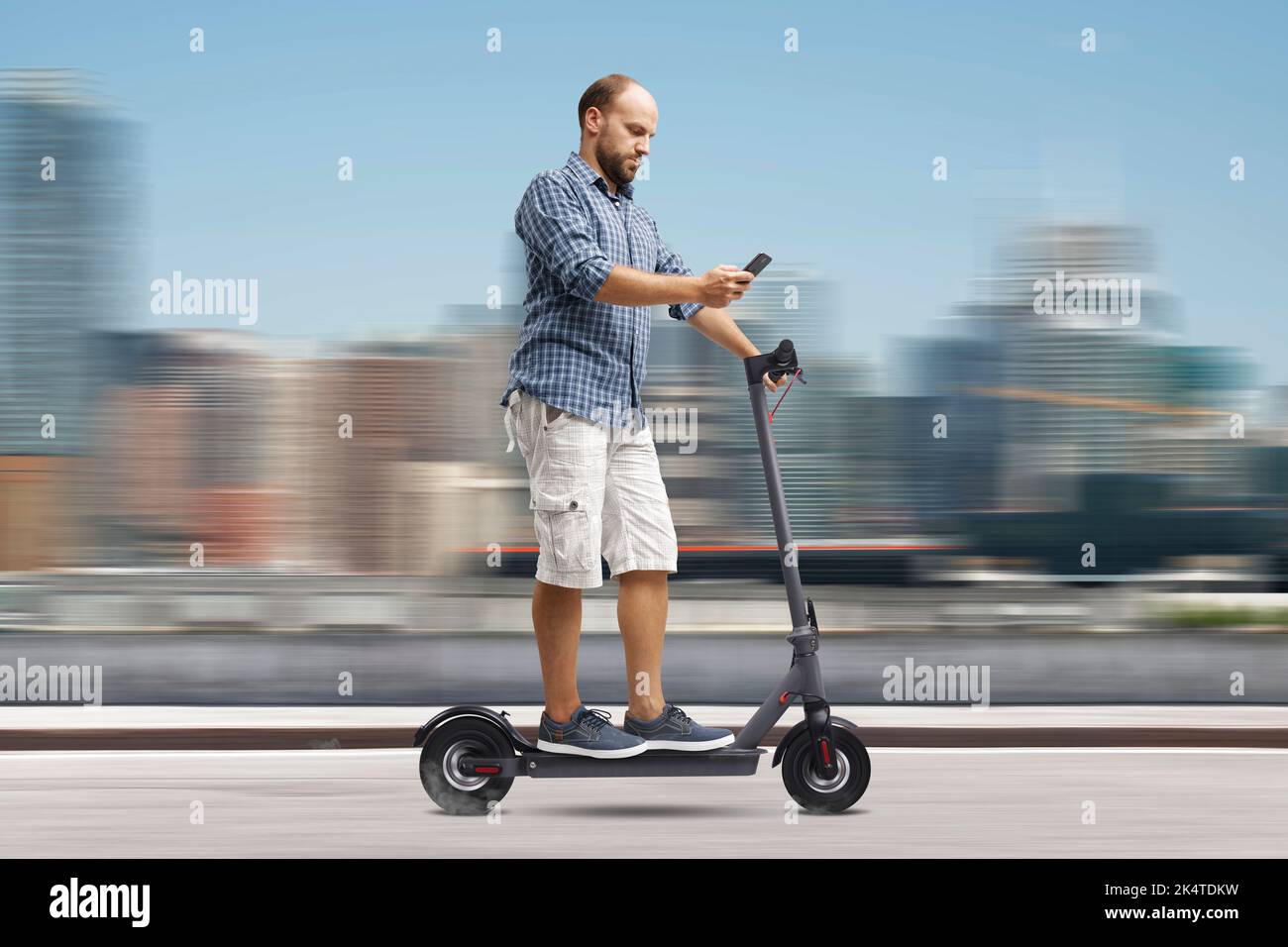 Careless man using a smartphone while riding an electric scooter, city ...