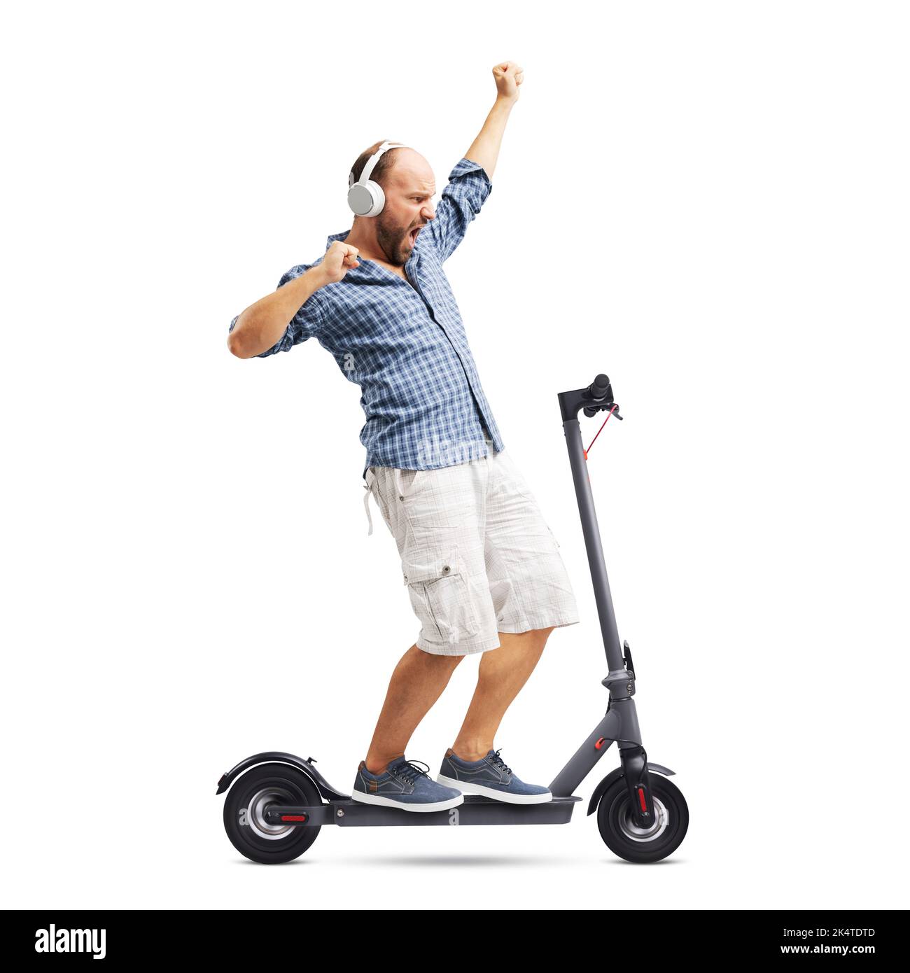Cheerful man listening to music and dancing while riding an electric scooter, isolated on white ...