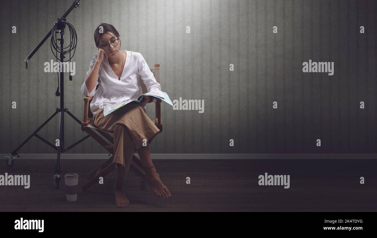 Focused professional actress sitting on the director's chair and ...