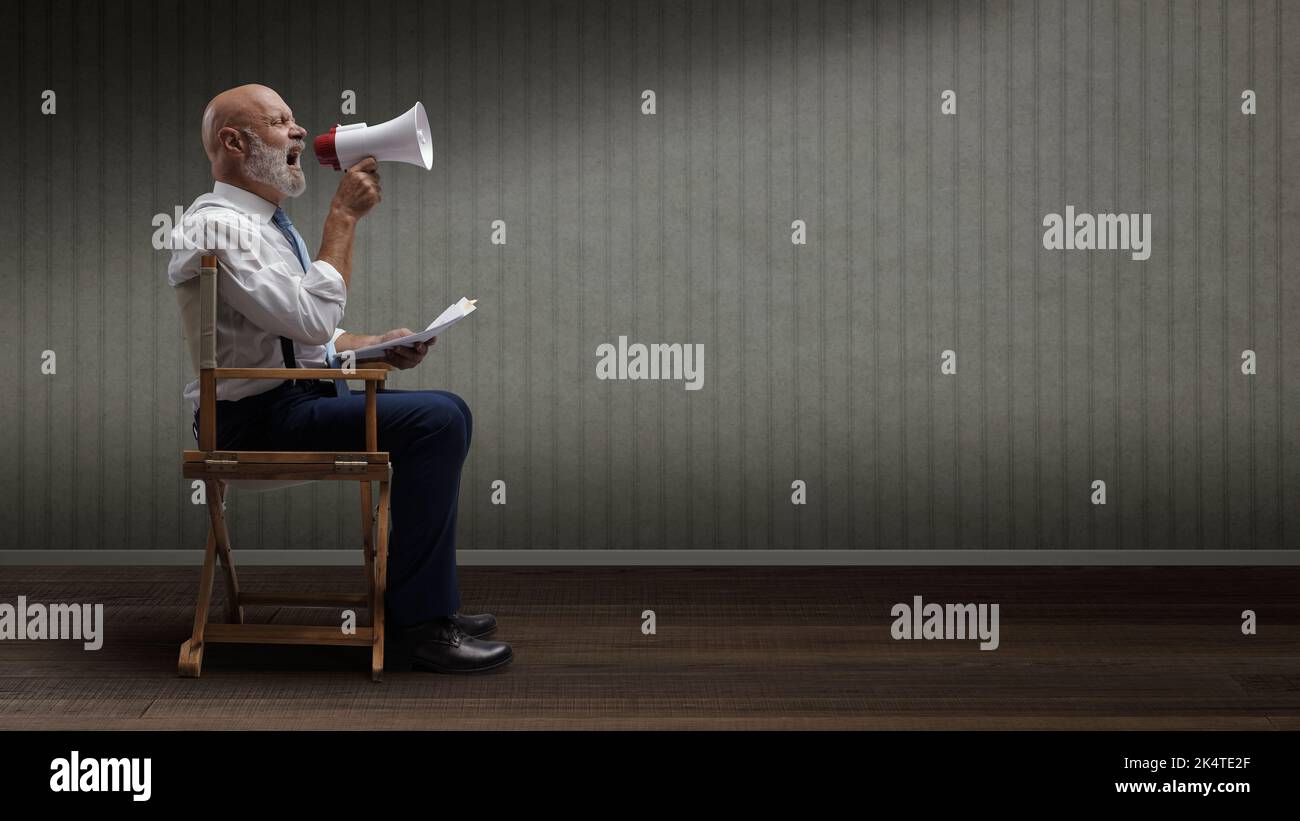 Confident professional film director sitting on the director's chair ...