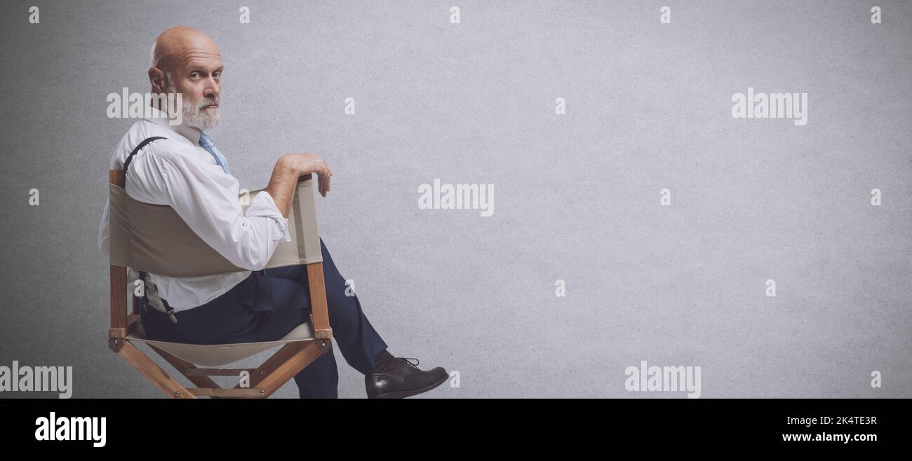 Confident film director sitting on the director's chair and looking at ...