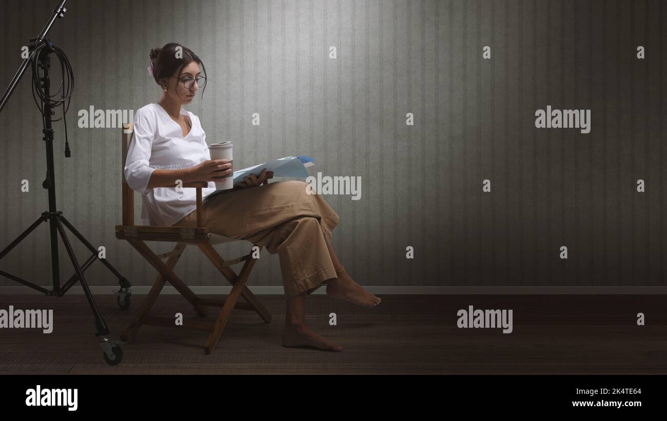 Focused professional actress sitting on the director's chair and ...