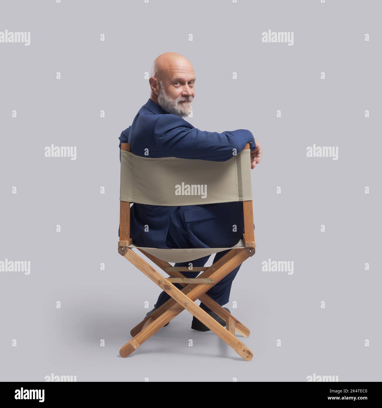 Confident film director sitting on the director's chair and looking at ...