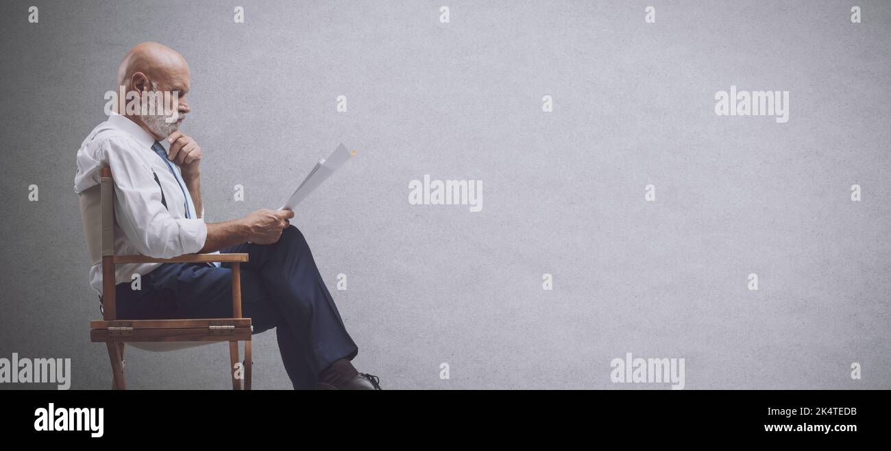 Professional film director sitting on the director's chair and reading ...