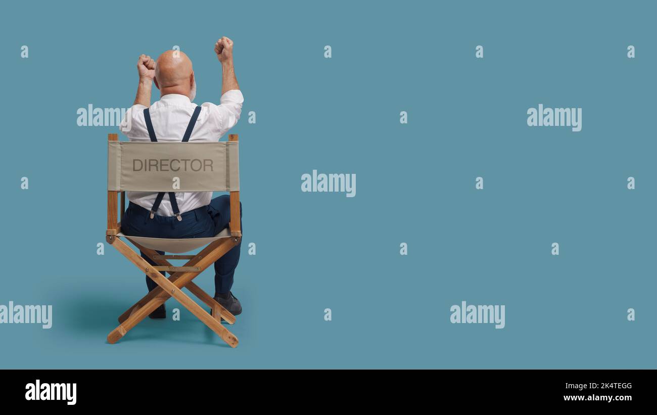 Angry disappointed film director sitting on the director's chair and ...