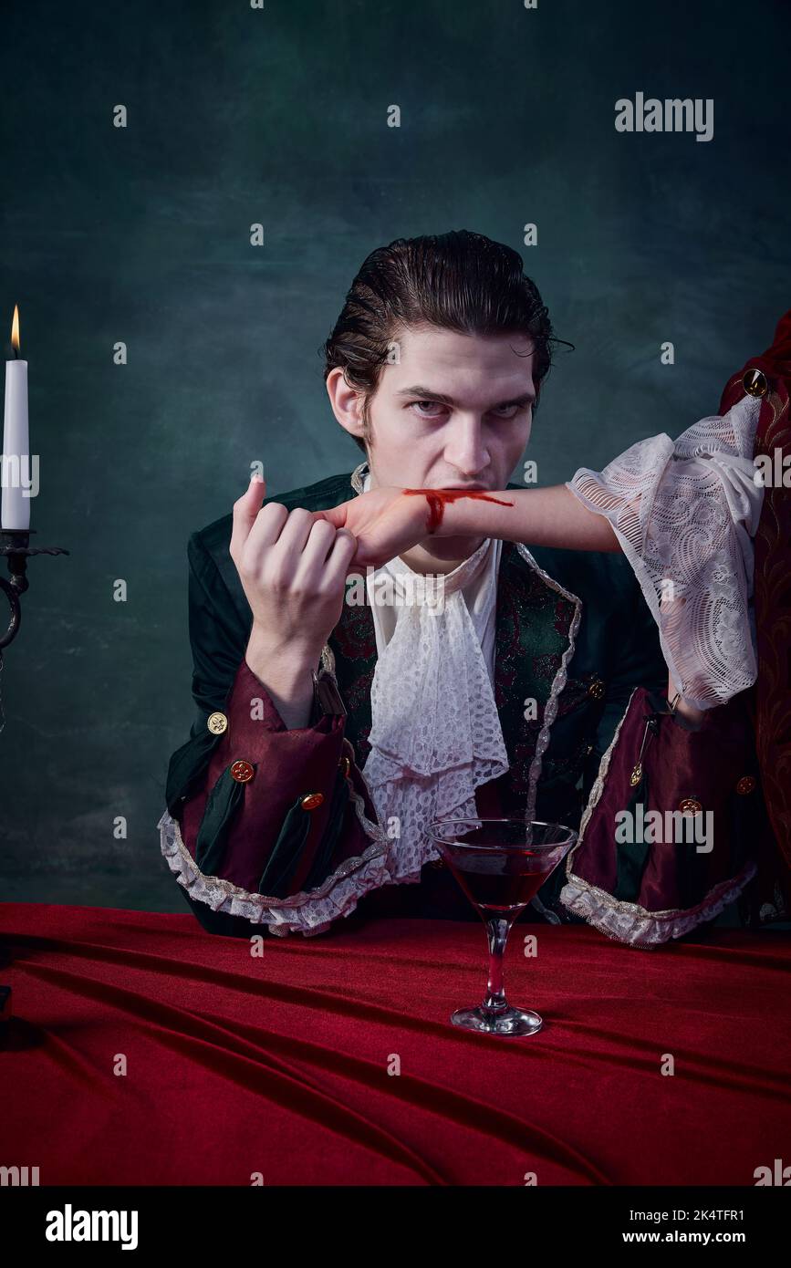 Portrait of endlessly young man in image of vampire drinking blood from ...