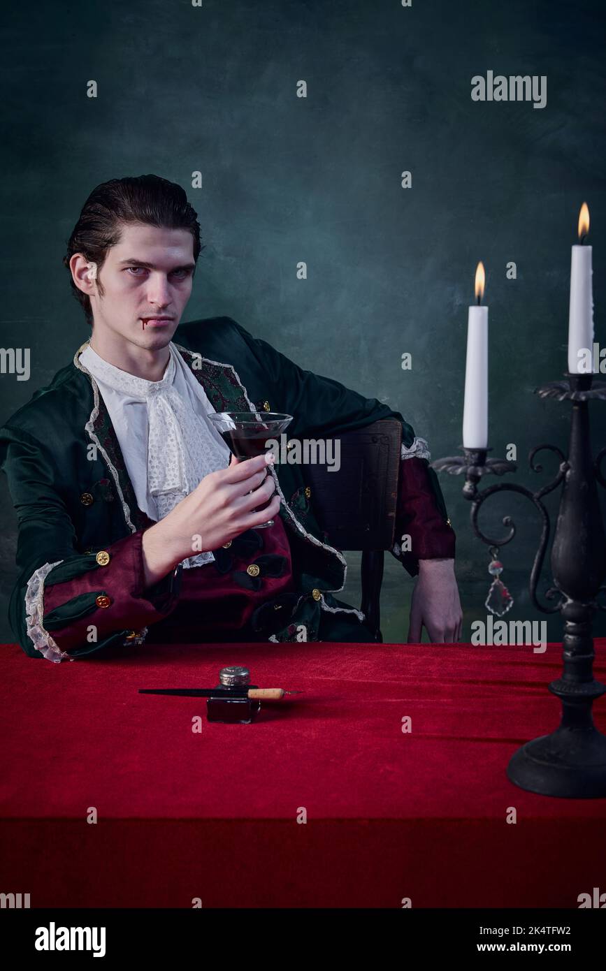 Portrait of fearful man in vintage medieval costume rising glass of ...