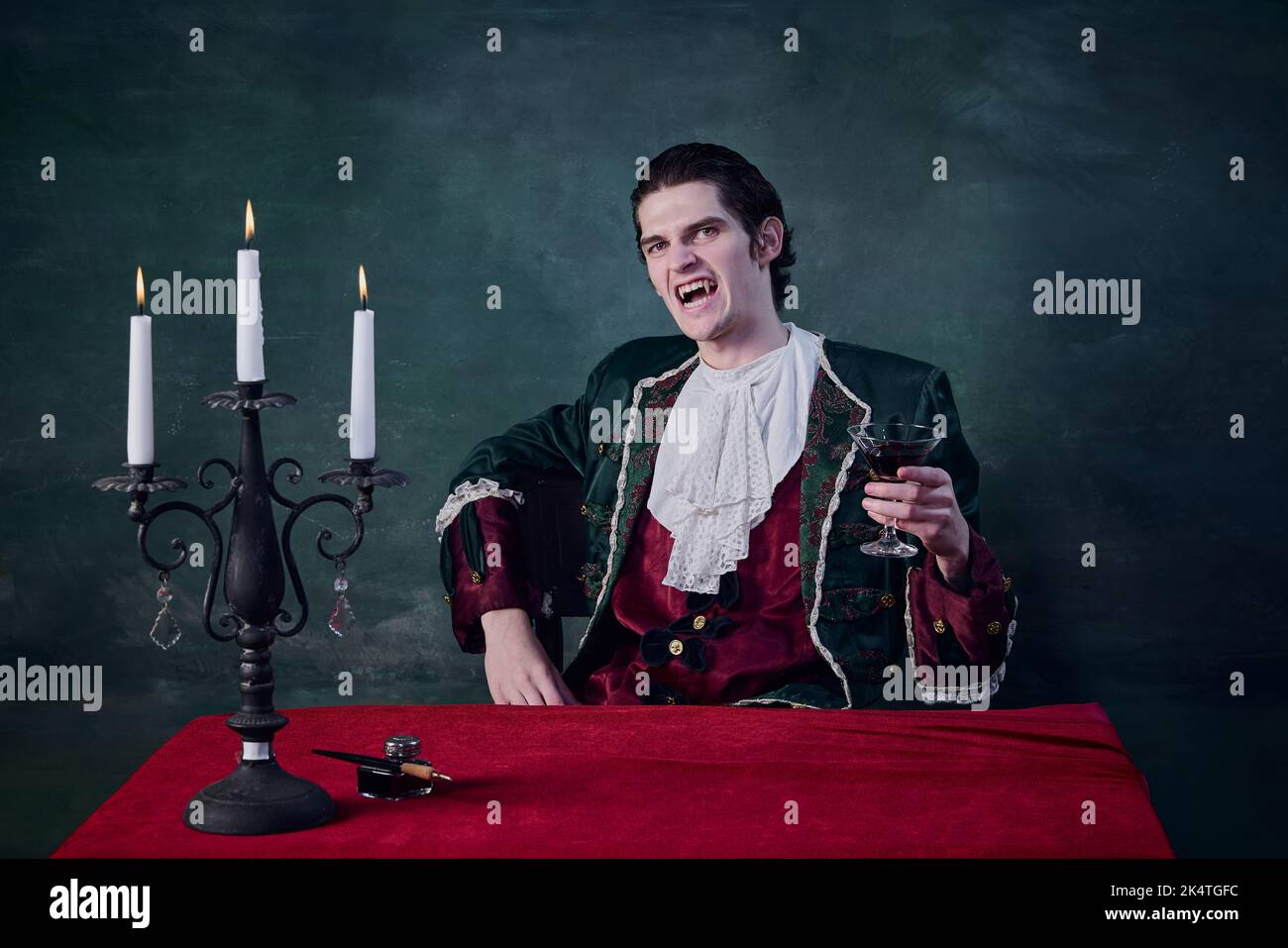 Portrait of terrifying man in image of vampire, Dracula rising glass of ...