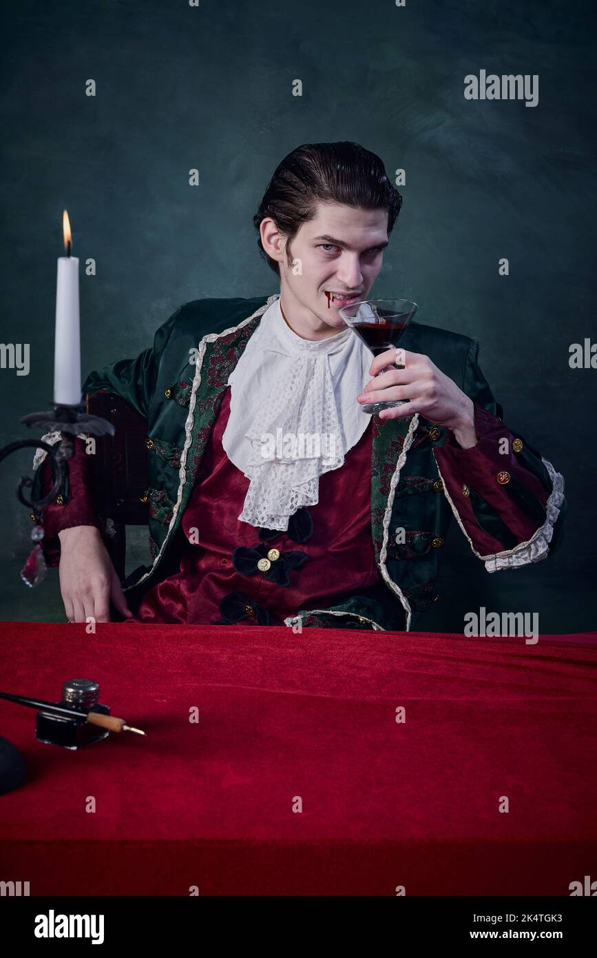 Portrait of terrifying man in image of vampire, Dracula drinking blood ...