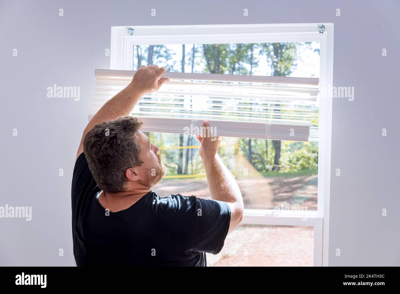 In a newly constructed house, a contractor is installing window blinds ...
