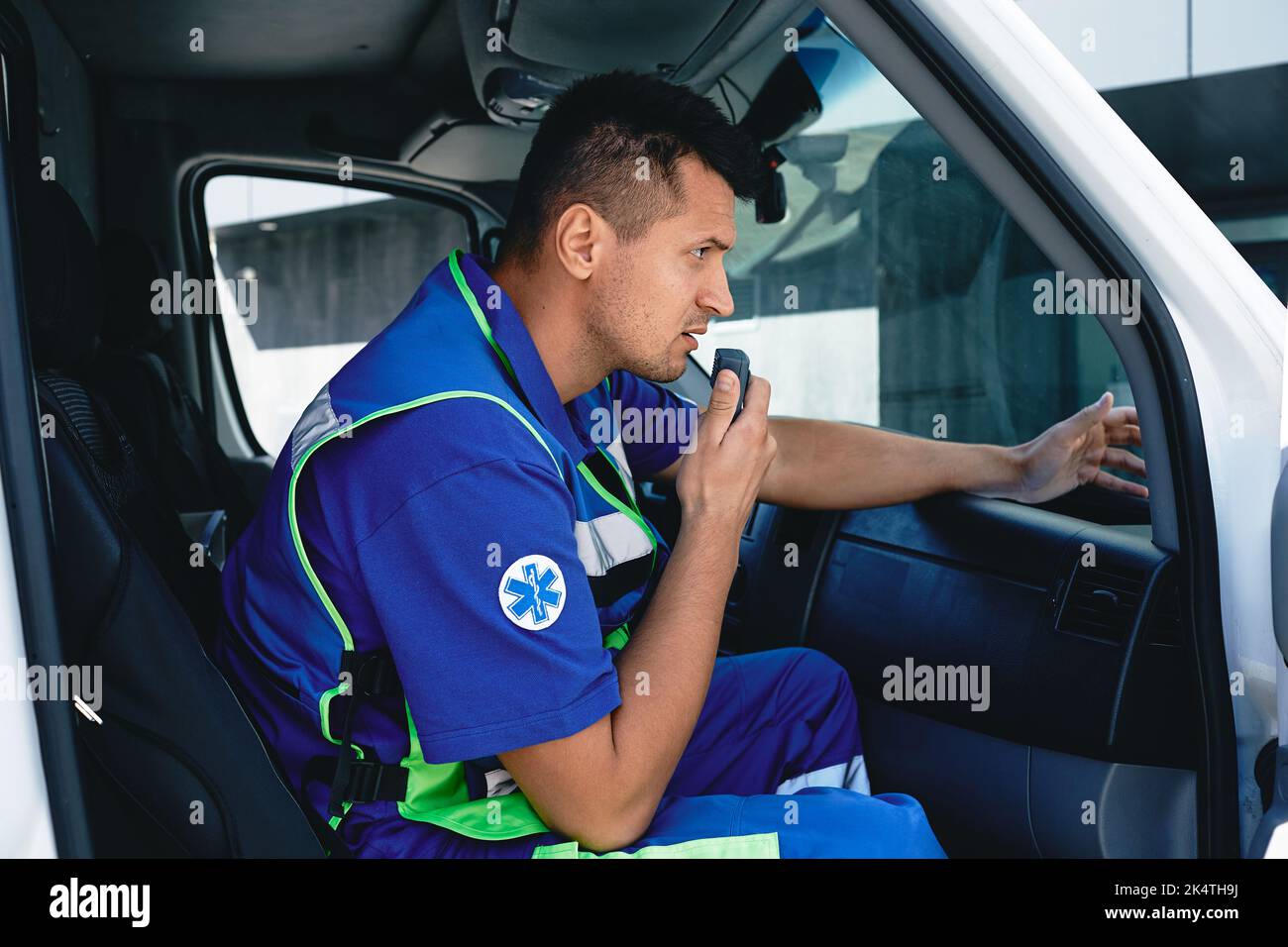 Concentrated male paramedic urgently communicating by portable radio ...