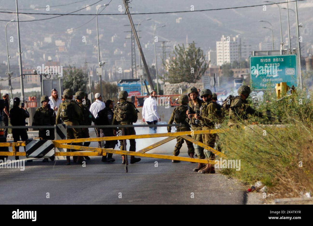 Israeli soldiers guard against Palestinians while Jewish settlers block ...