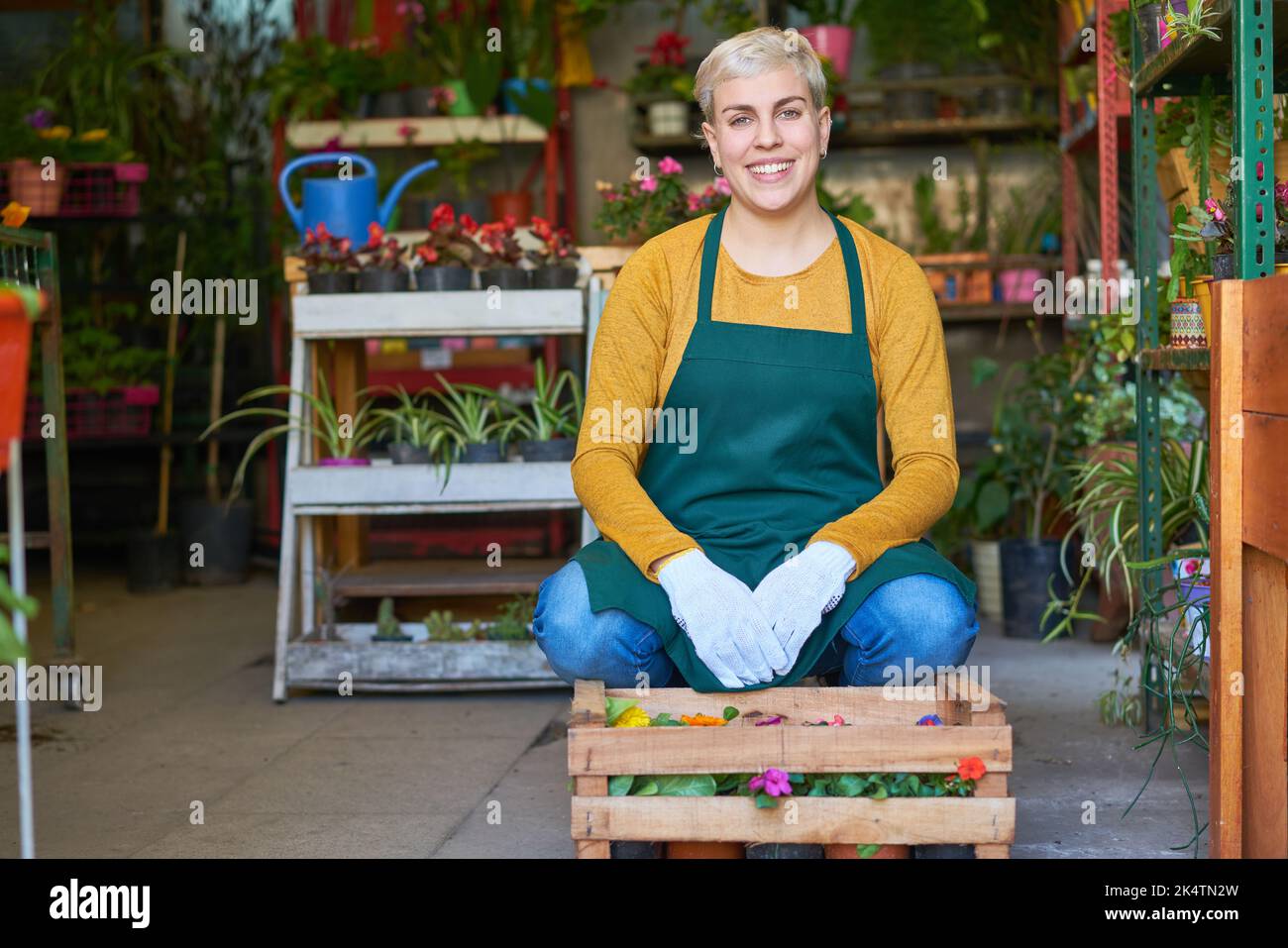 Happy young woman gardener apprentice with a box of plants in the ...