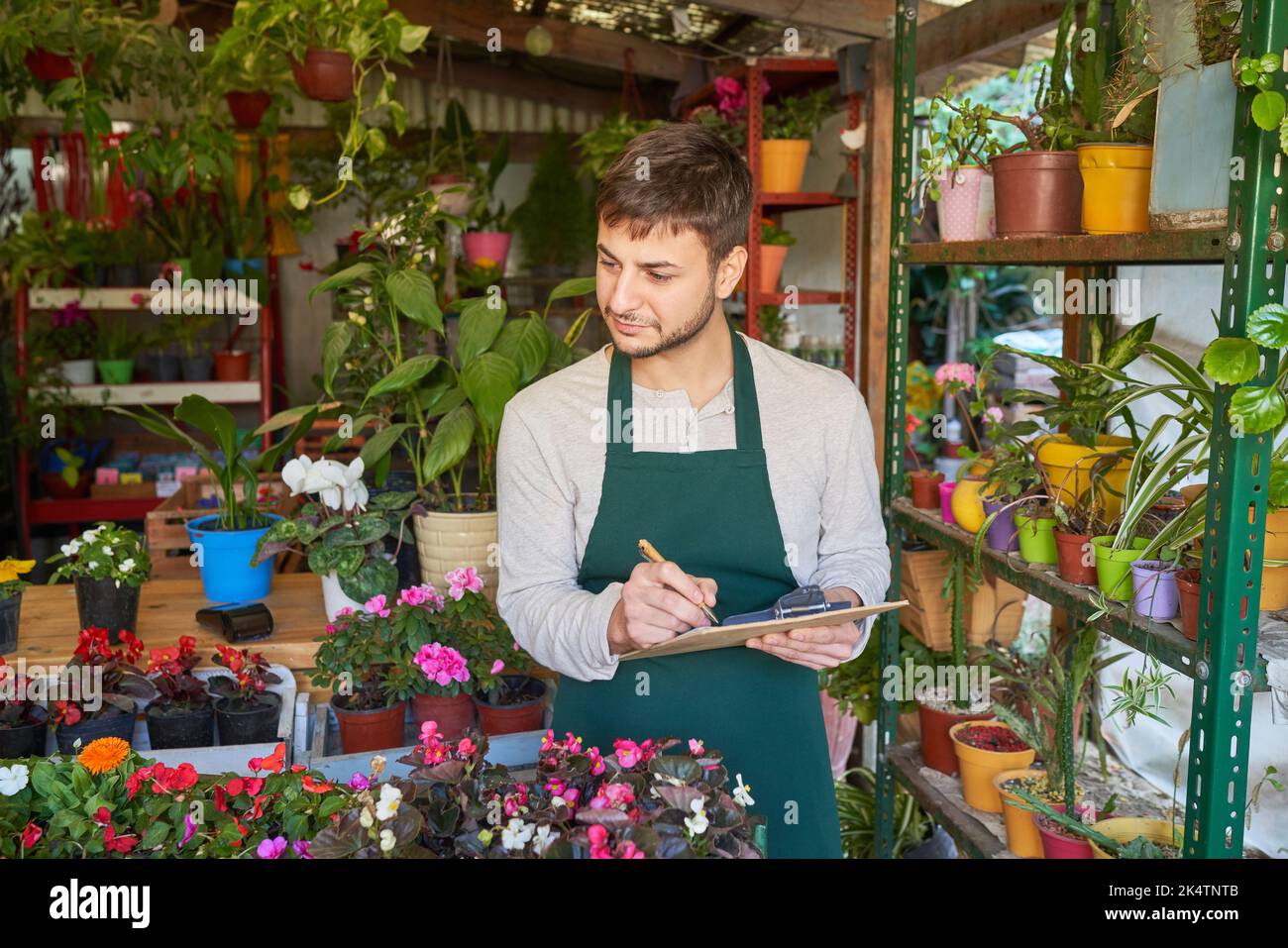 Young gardener with clipboard doing inventory and quality control in ...