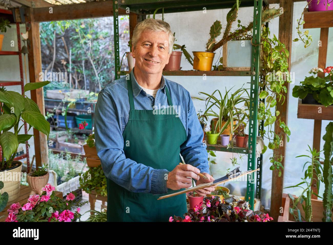 Elderly florist in the flower shop taking inventory or with a checklist ...
