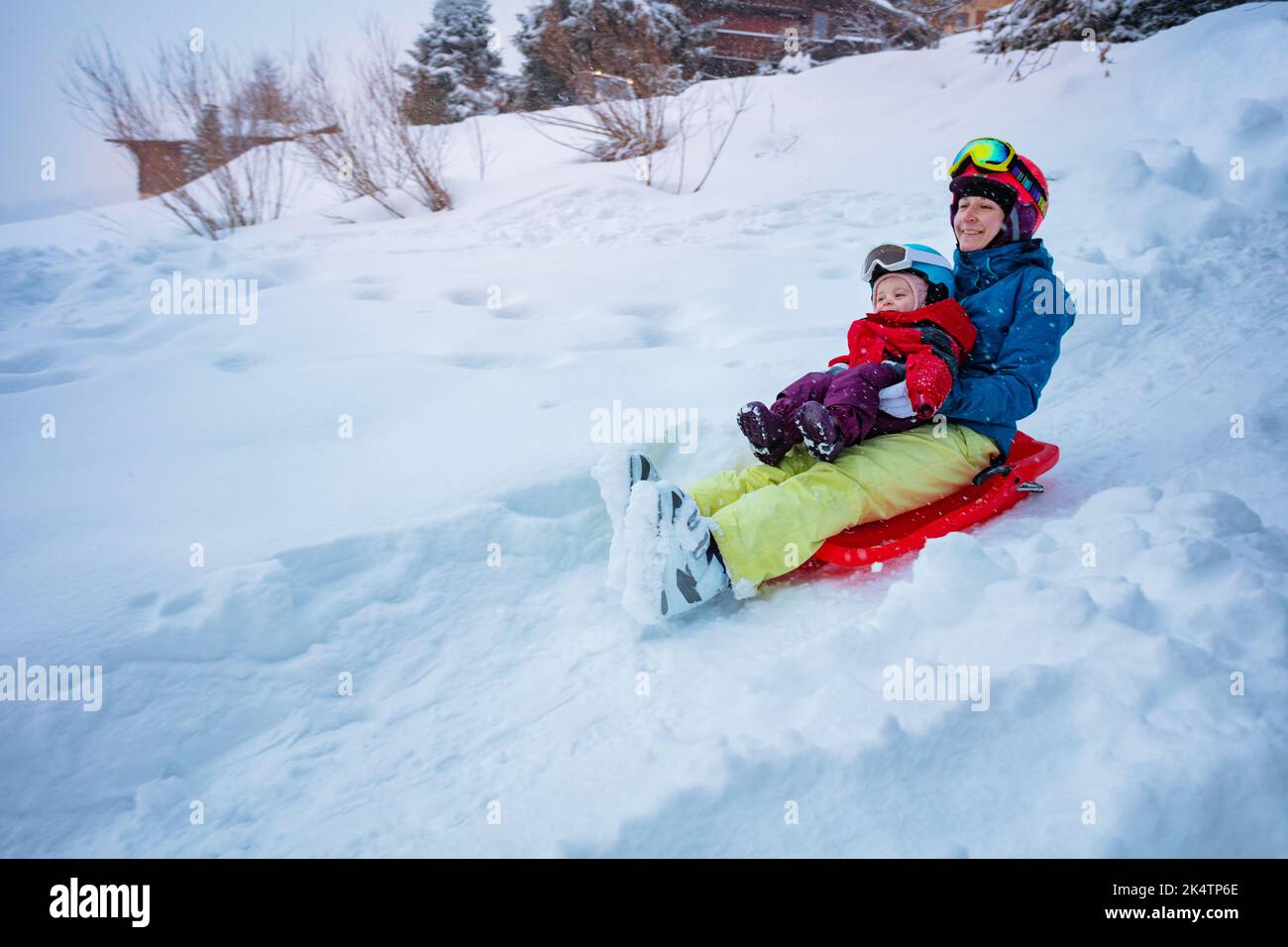 Mother with little girl sled downhill on sledge from the hill Stock ...