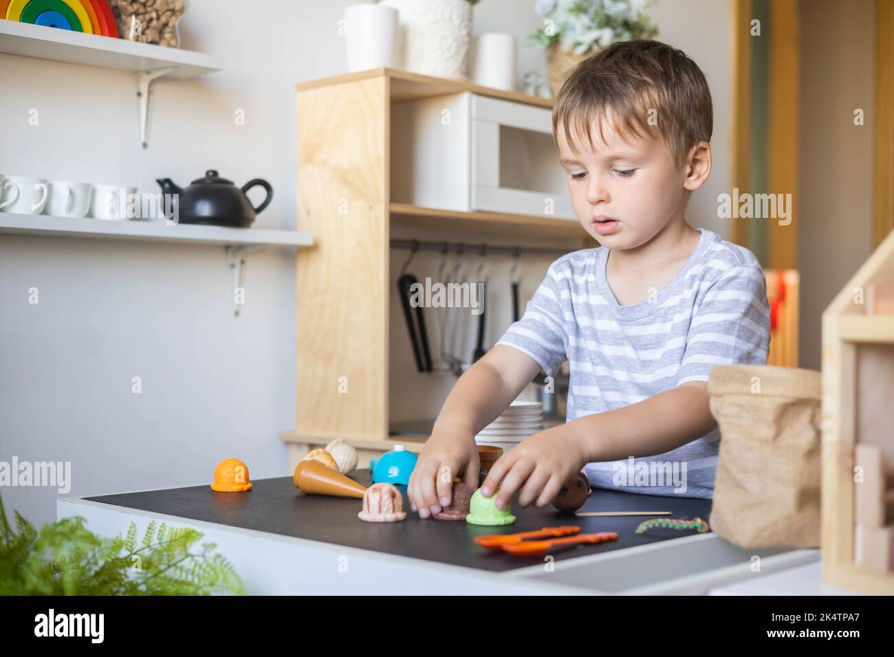 Cute male kid preparing toy food boiling vegetables on cooker at ...