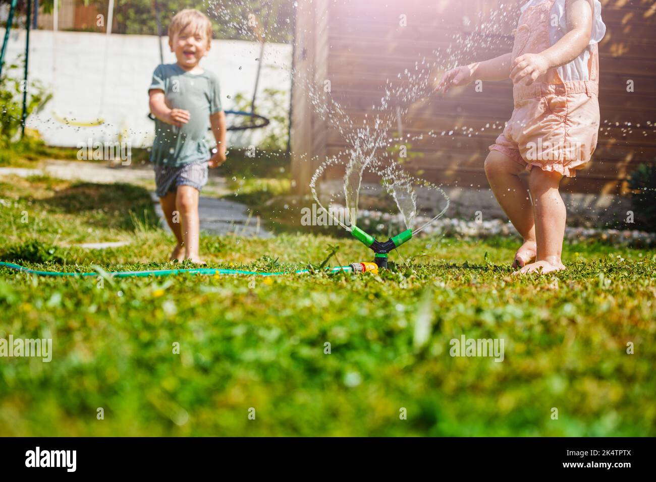 Boy and girl have fun in the garden - playing with water on lawn Stock ...