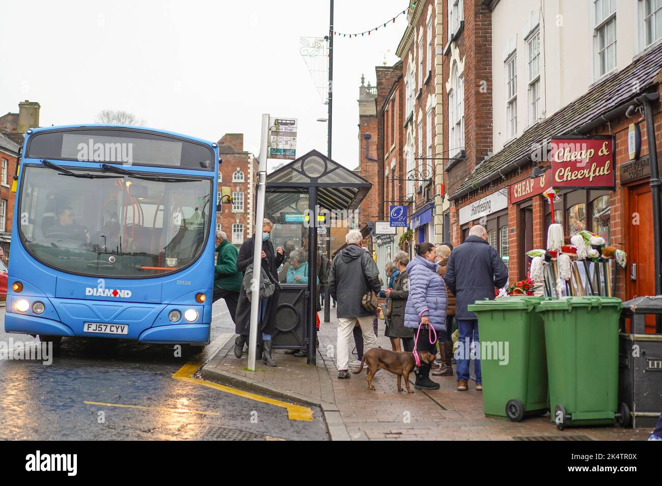 People getting on and off a blue Diamond bus at a busy bus stop in a ...