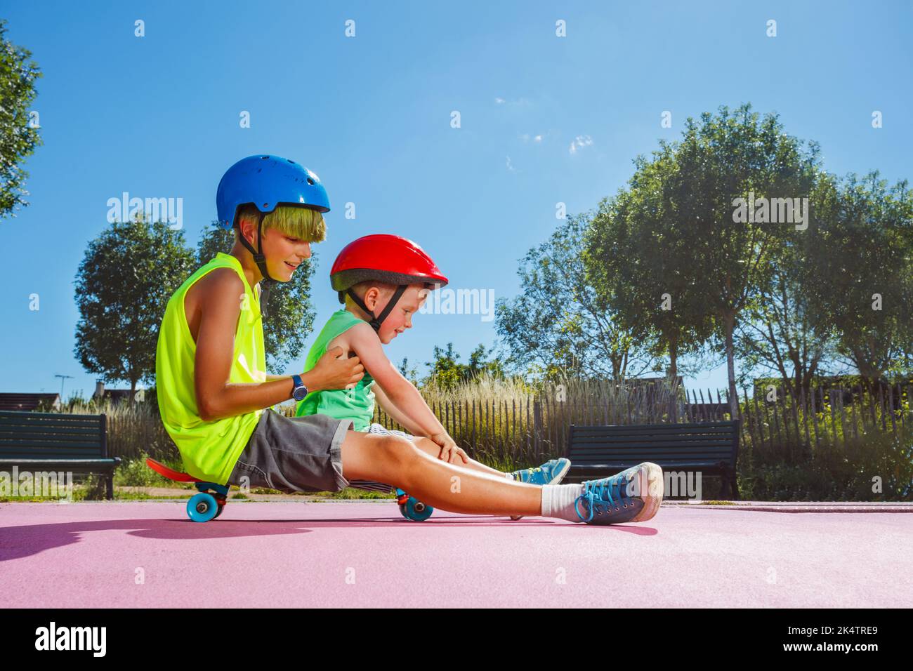 Two brothers sit on the skate riding together in helmets Stock Photo ...