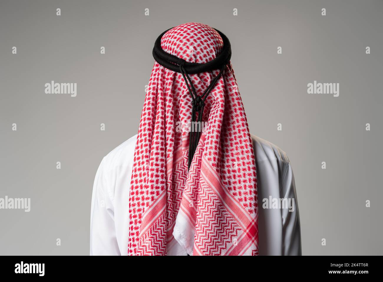 Back view of young Arab man standing on gray background Stock Photo - Alamy