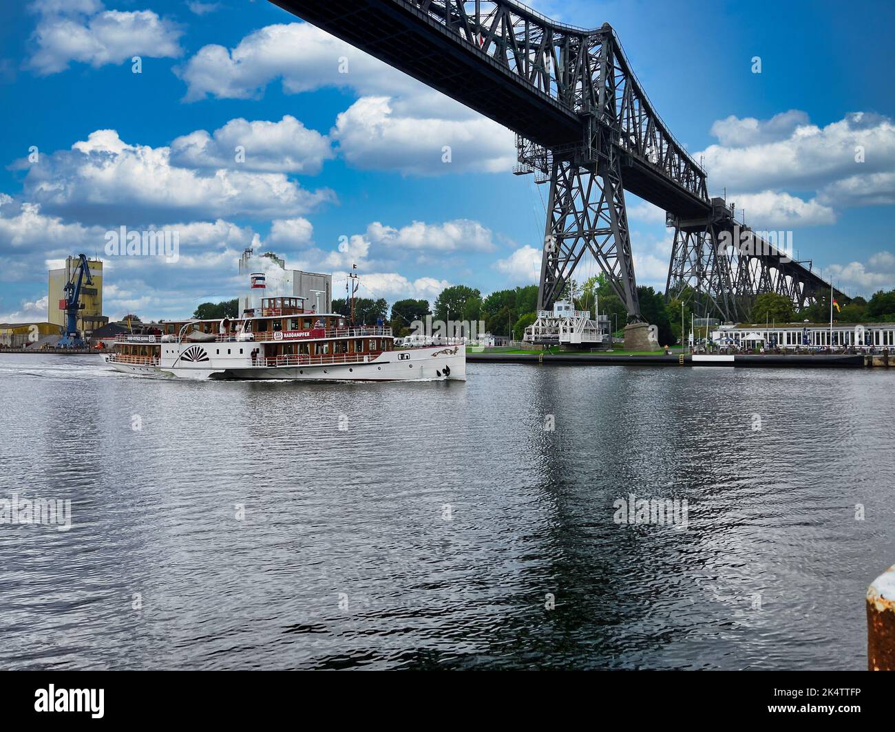 Paddle steamer under railroad high bridge with floating ferry behind ...