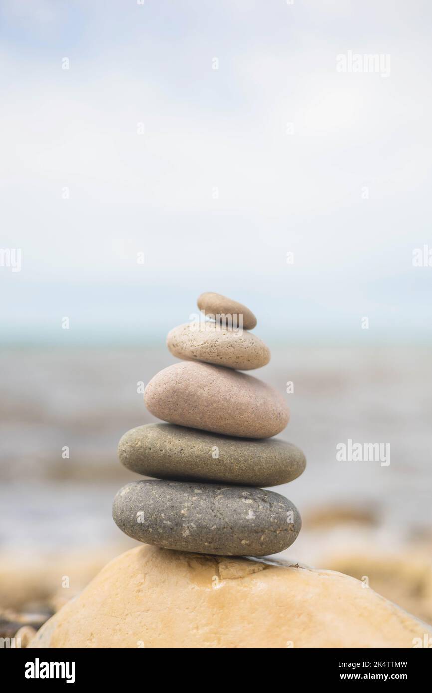 Pebble tower on sunny beach sea wave splashing water balance pyramid ...