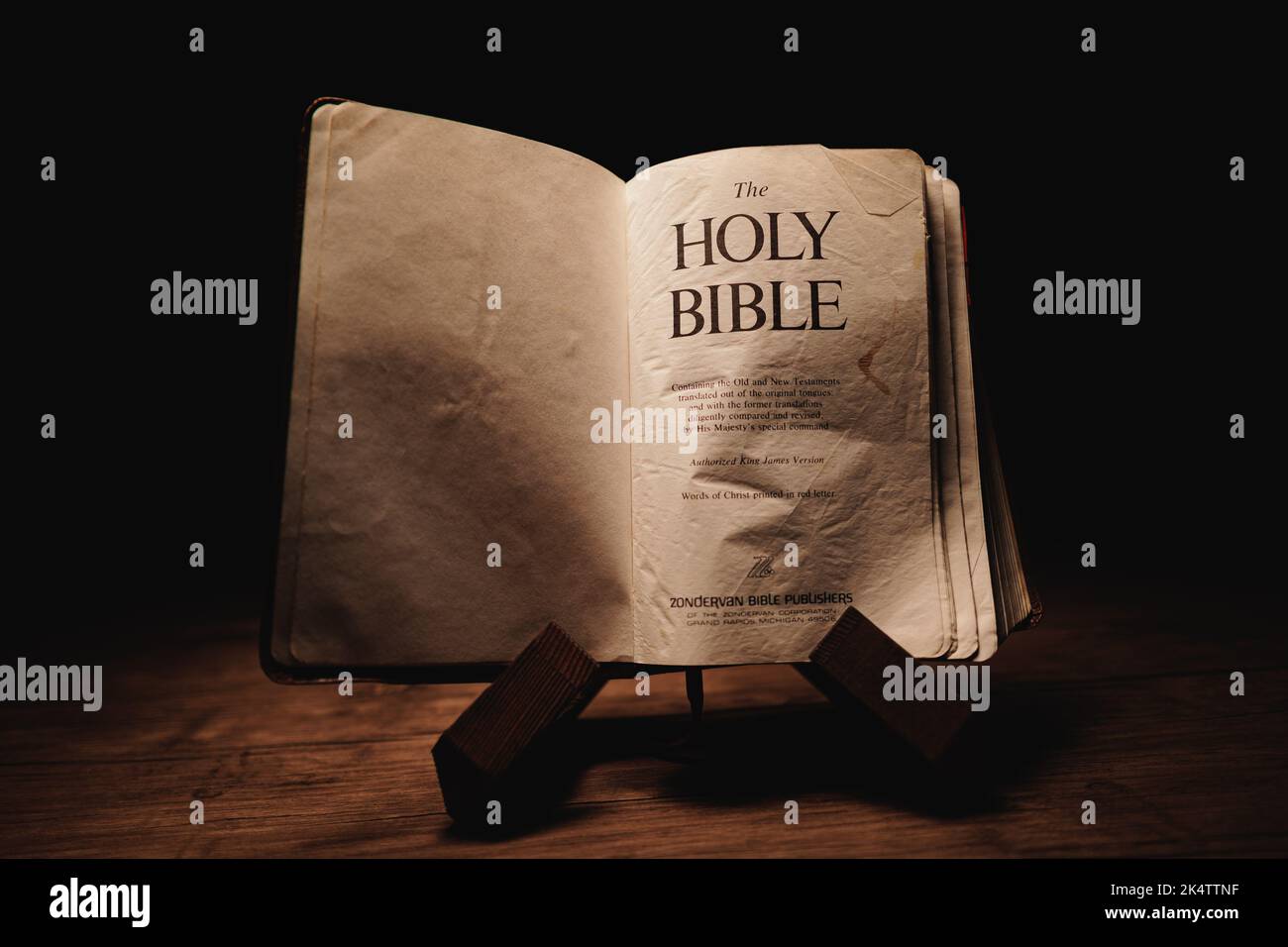 An open bible placed on a wooden book stand with a dark background ...