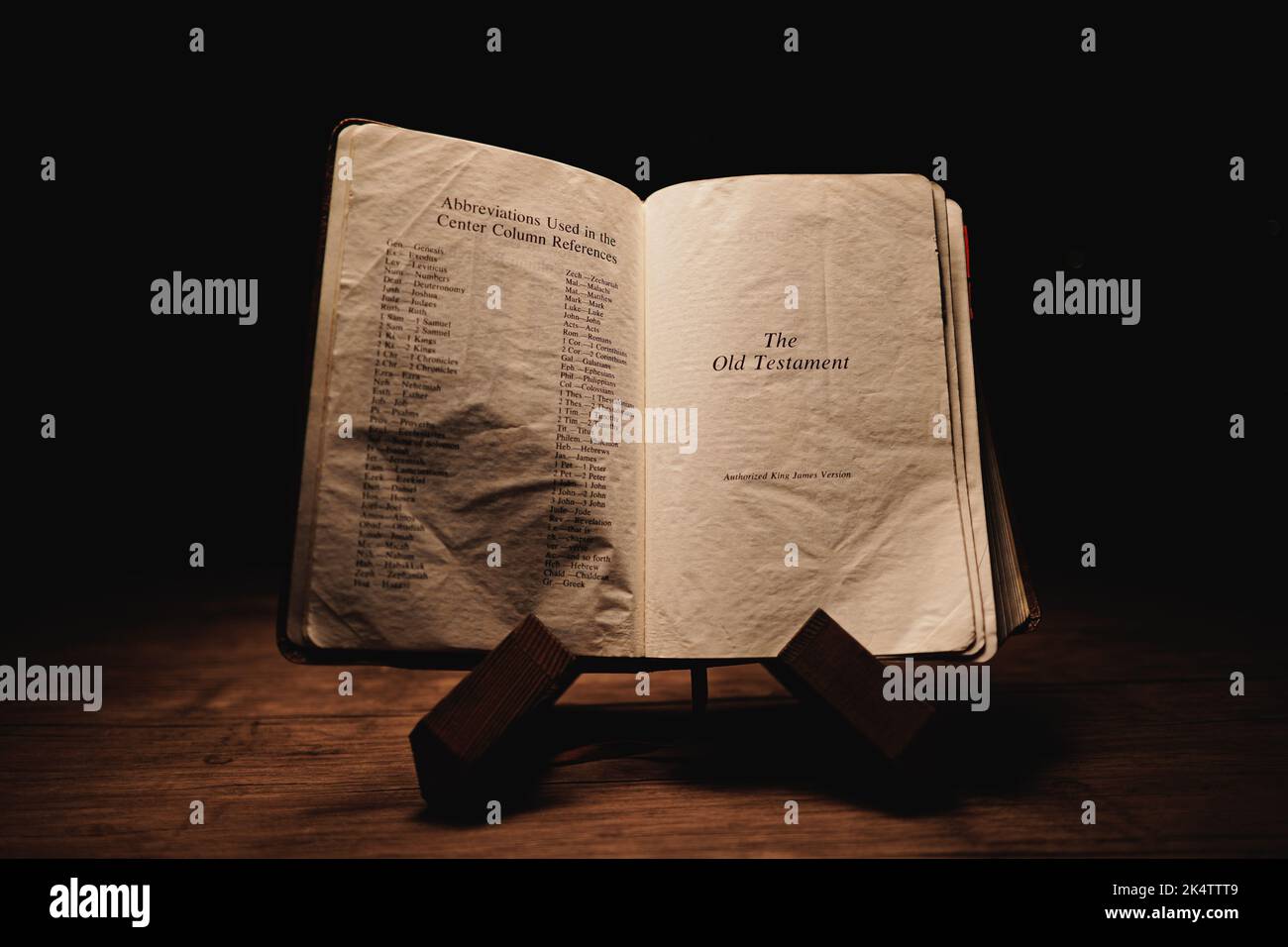 An open bible placed on a wooden book stand with a dark background ...