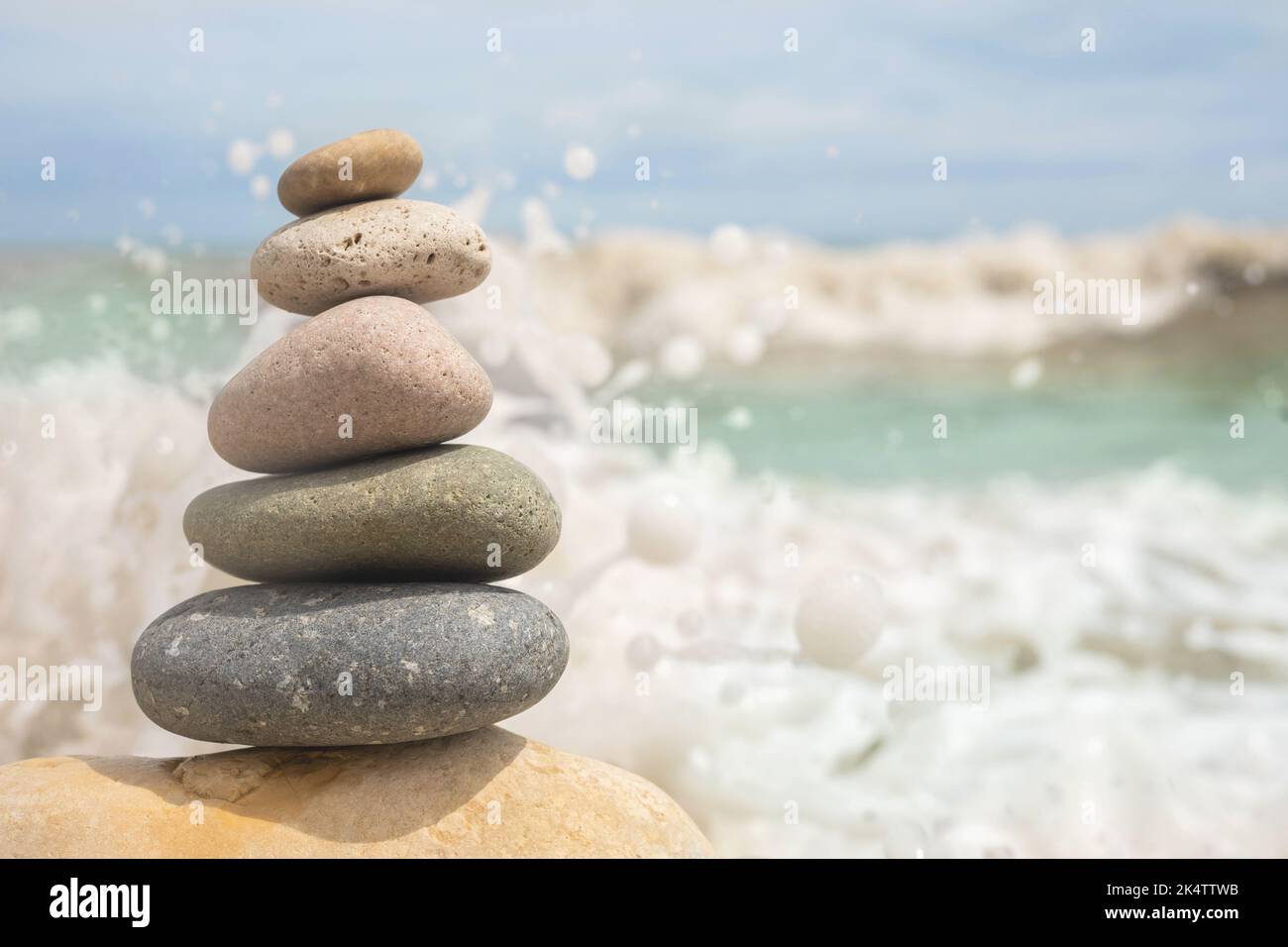 Pebble tower on sunny beach sea wave splashing water balance pyramid ...