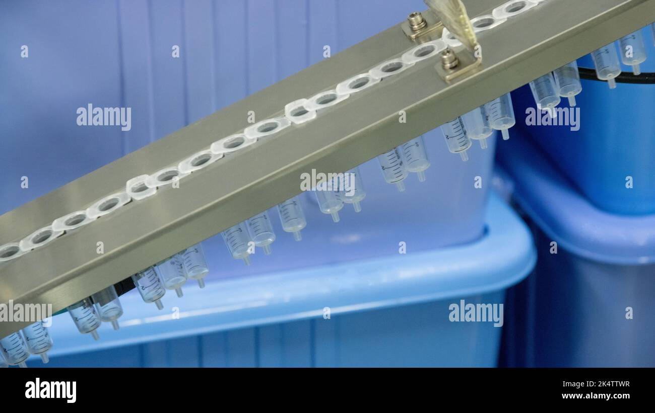 A pack of transparent medical syringes arranged in a row in a metallic ...