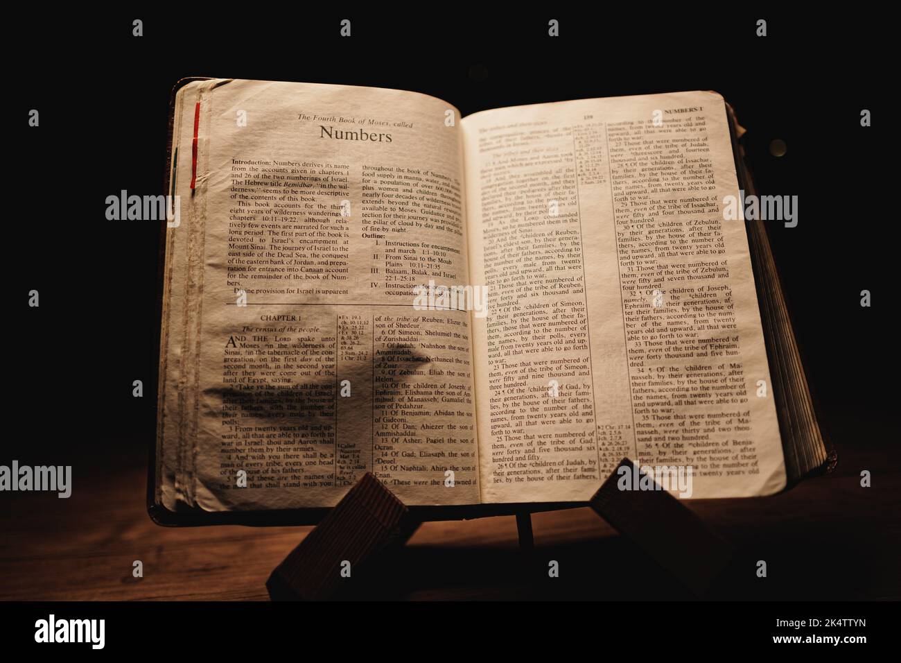 An open bible placed on a wooden book stand with a dark background ...