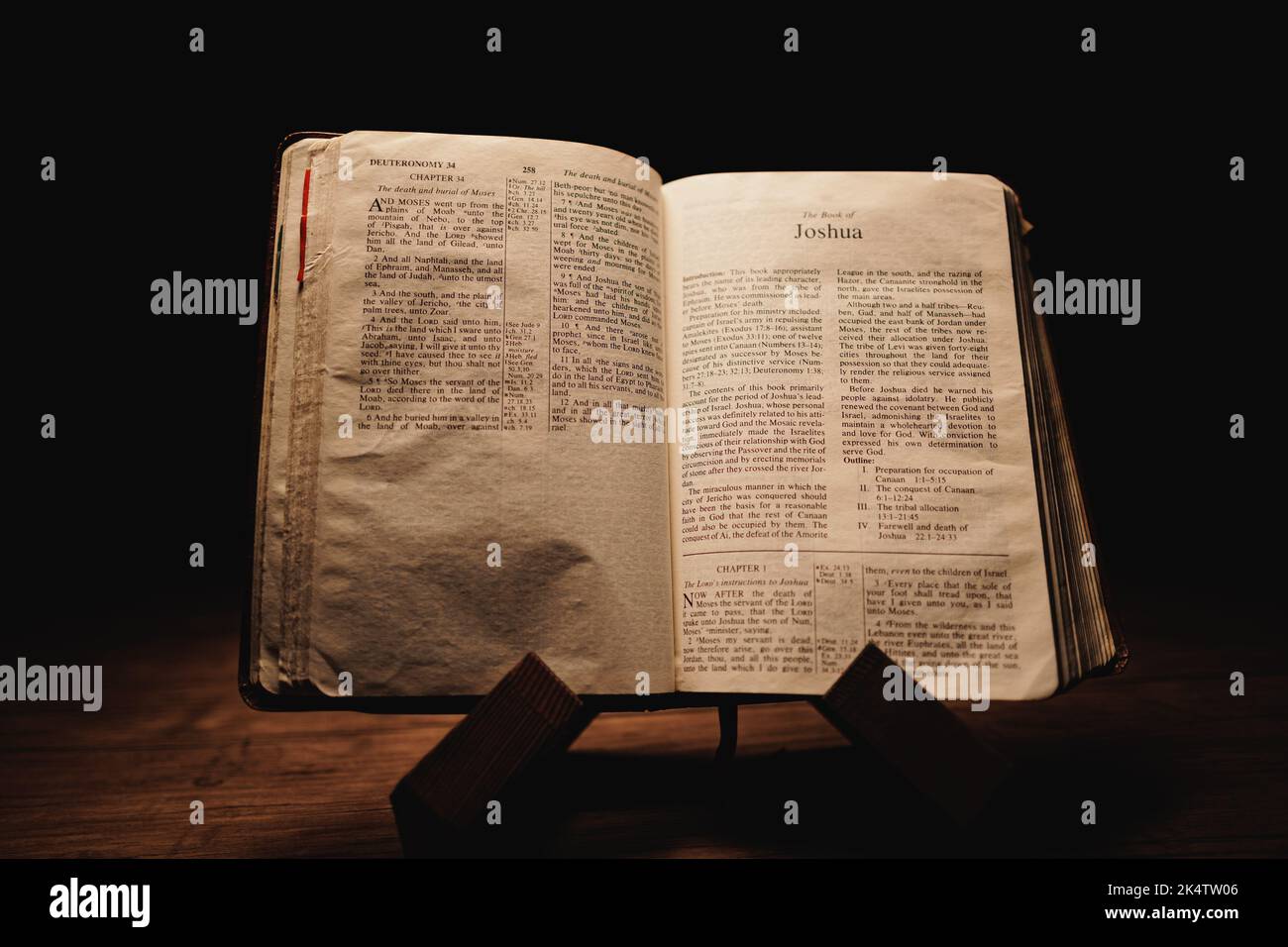 An open bible placed on a wooden book stand with a dark background ...