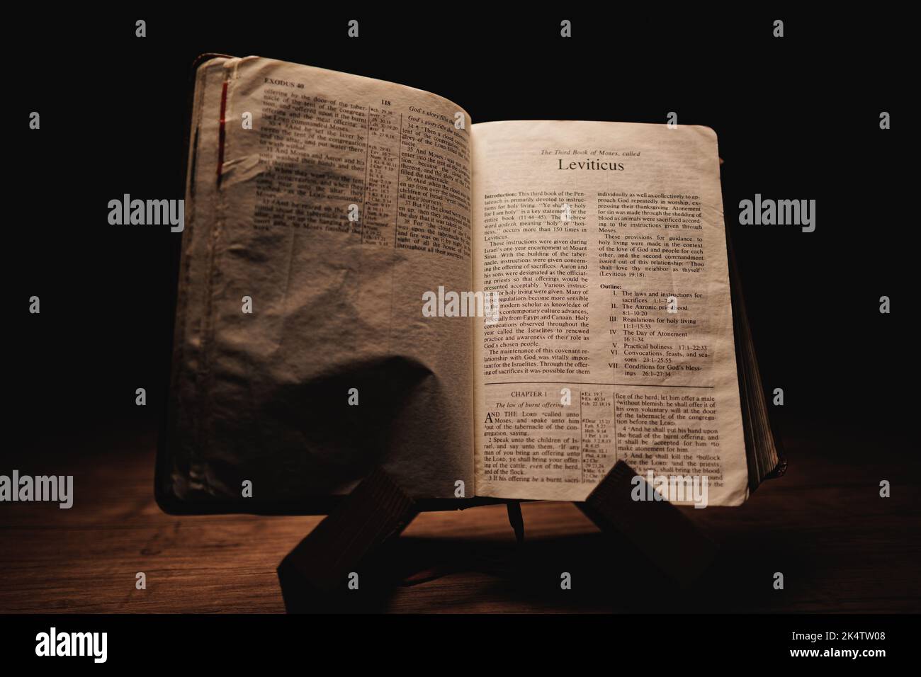 An open bible placed on a wooden book stand with a dark background ...