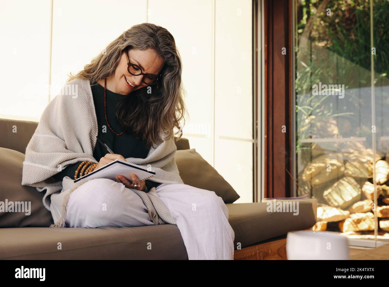 Journaling during retirement. Mature woman smiling happily while ...