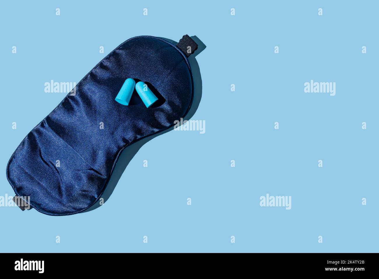 Pair of blue ear plugs and sleeping mask on light blue background, flat ...