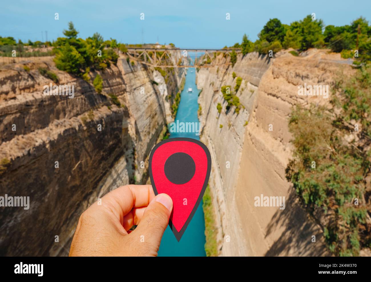 the hand of a man holding a red marker pointing the Corinth Canal, in ...
