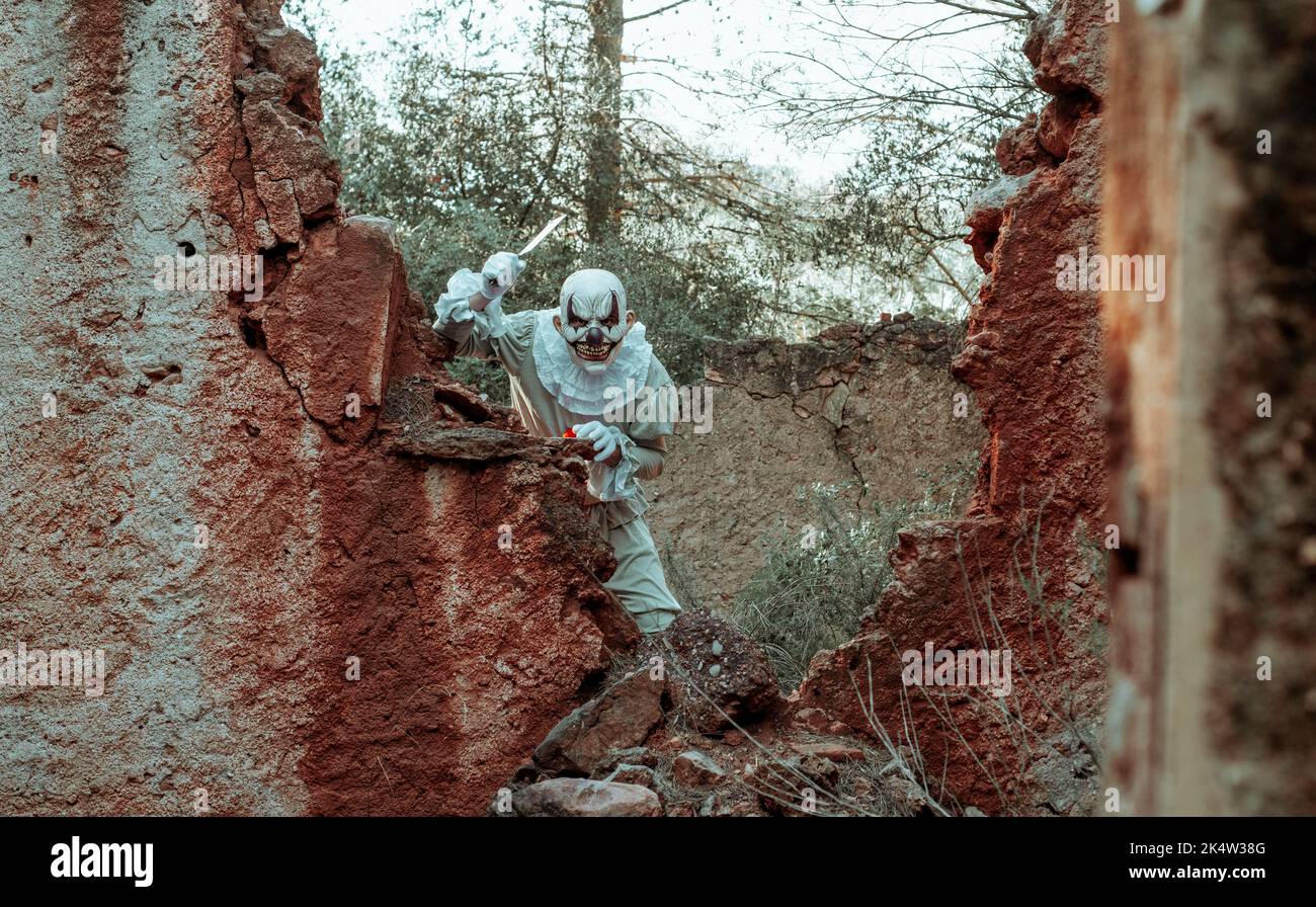 a creepy evil clown, wearing a gray costume with white ruffles, neck ...
