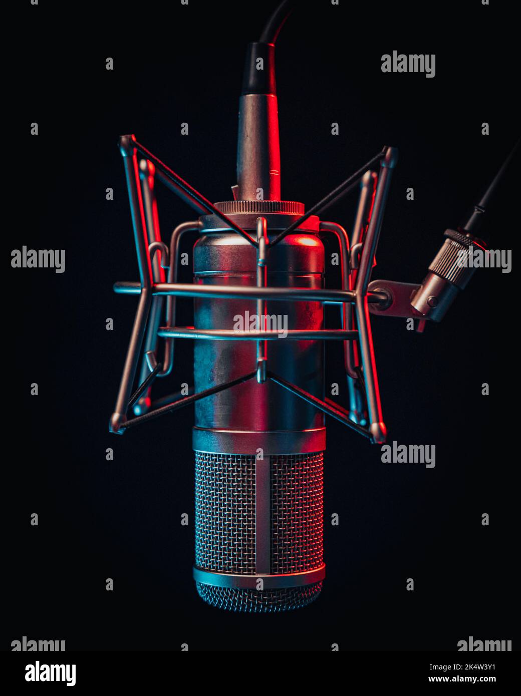 Isolated studio microphone lighted by red and blue light in dark ...