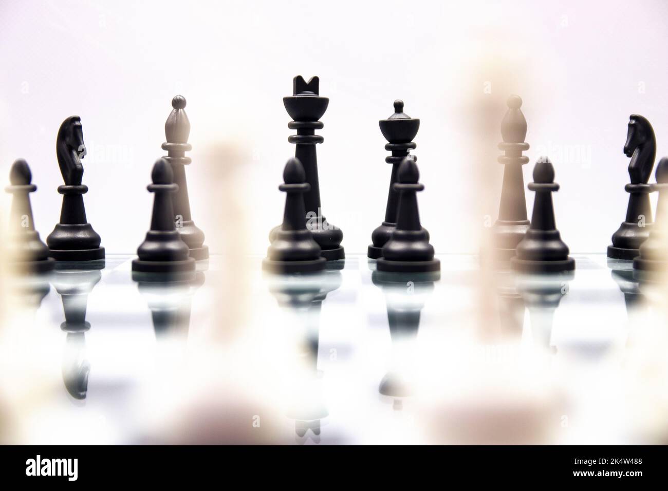 A selective focus of black chess pieces on a reflective chessboard on ...