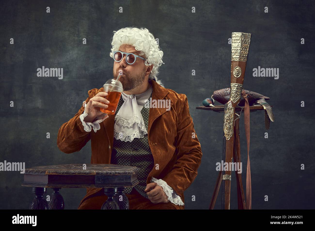 Drinking lemonade. Vintage portrait of young man in brown vintage suit ...