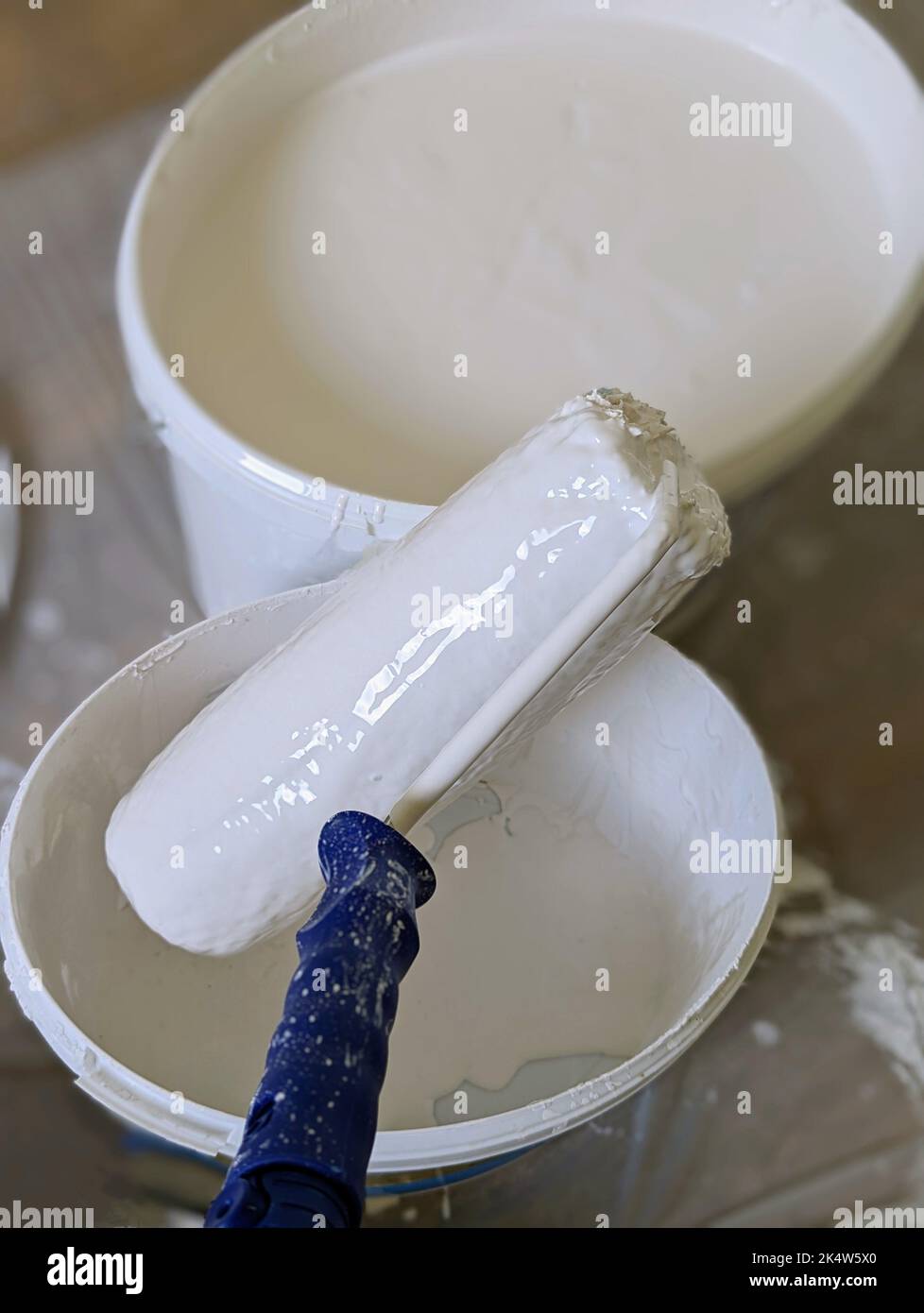 A vertical high angle view of paint roller with white paint on ca ...