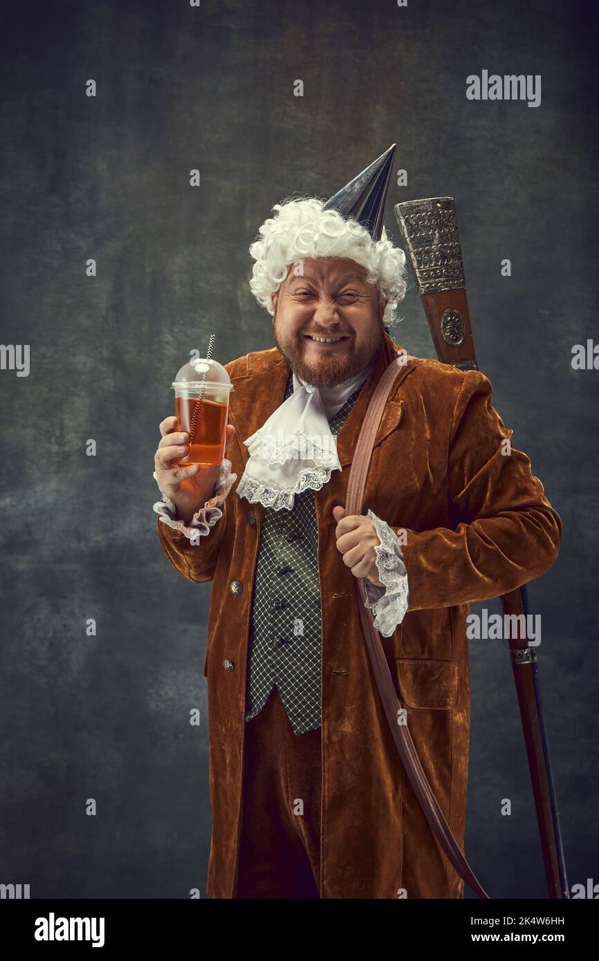 Funny young man in brown vintage suit and white wig like medieval royal ...