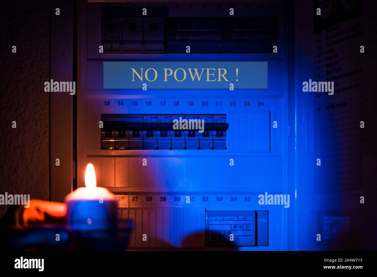 hand with candle in darkness room on electricity switch box. Power ...